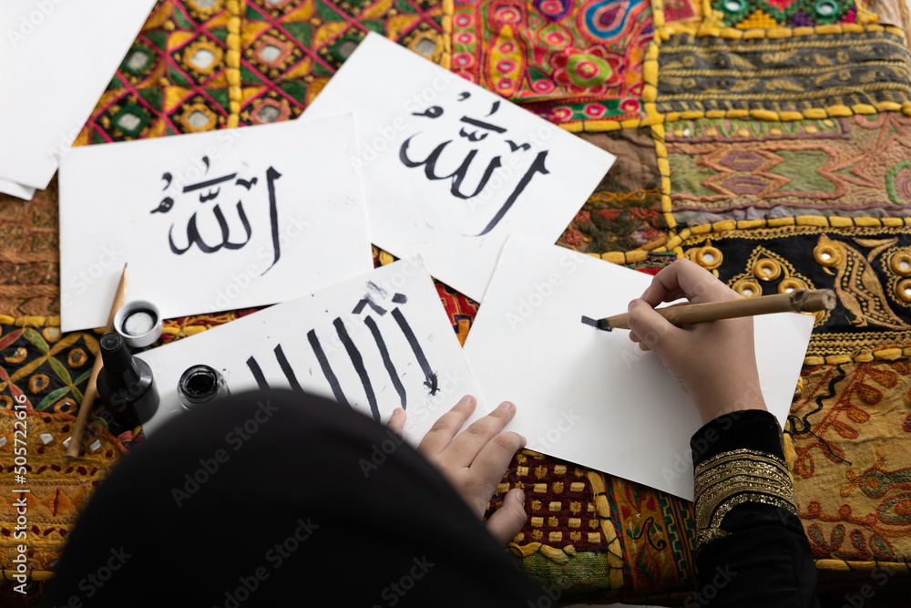 close up muslim girl hands writing Arabic text with bamboo pens and ...