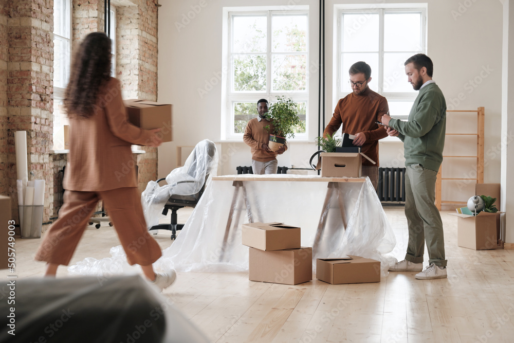 Group of men standing at desk covered with polyethylene and unpacking ...