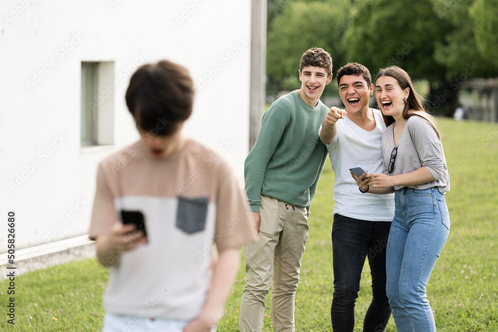 Group of teenagers laughing and pointing at boy. Cyber bullying concept ...