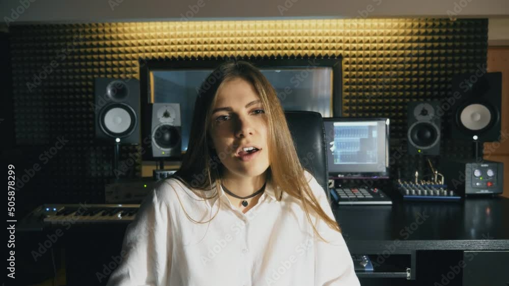 Portrait of beautiful girl singing in sound studio. Young female singer ...