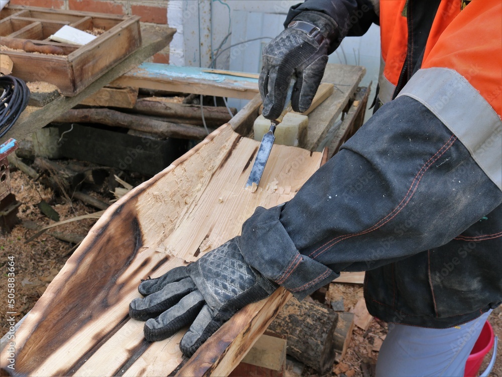 scraping a niche in a burnt wooden material in the process of making a ...