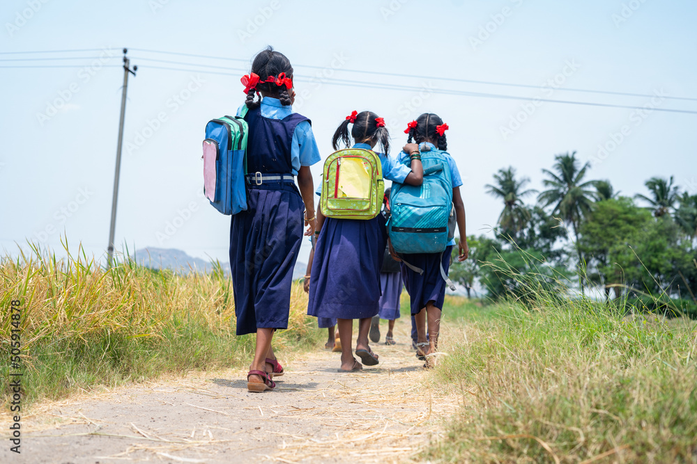 Back view shot of village kids in uniform going home from school after ...
