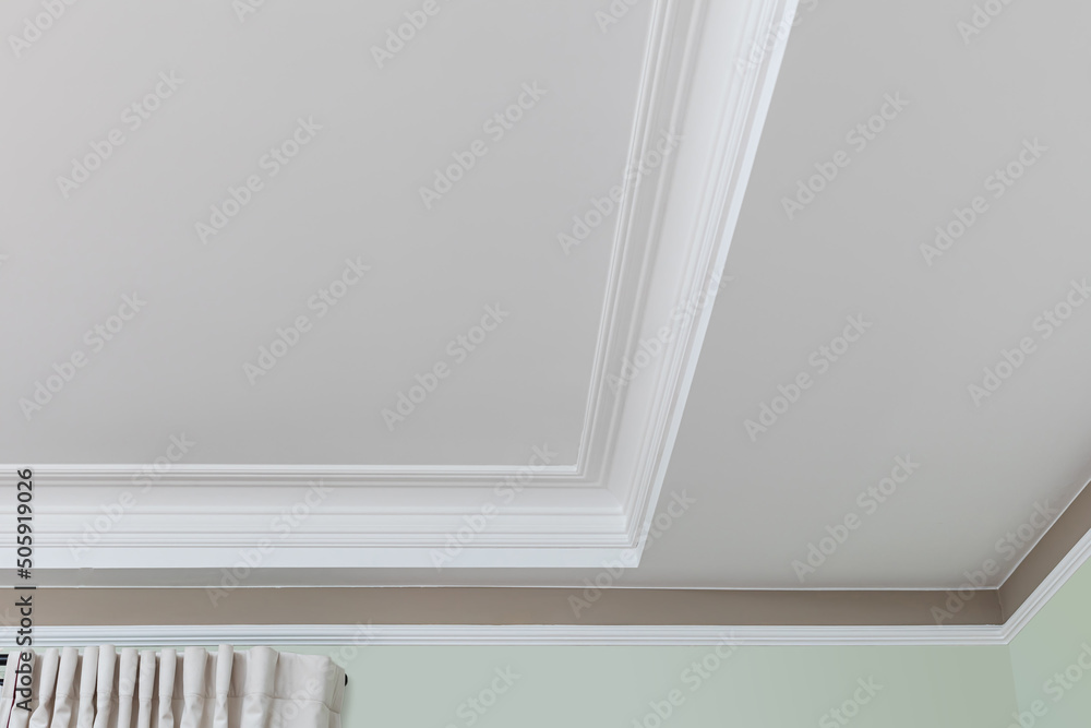 Angular ceiling skirting made of classic white crown moldings. Close-up ...