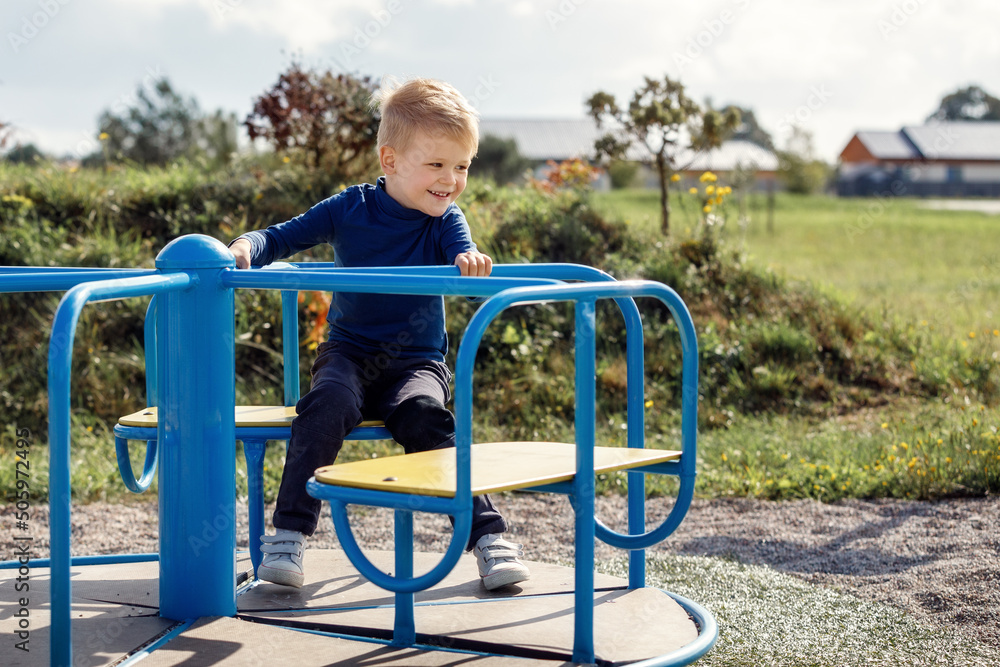 Child on merry-go-round. Boy spins on carousel for children on ...