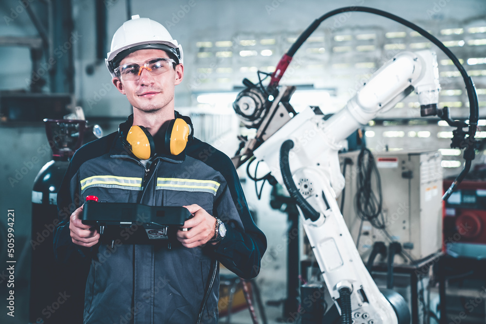Young factory worker working with adept robotic arm in a workshop ...