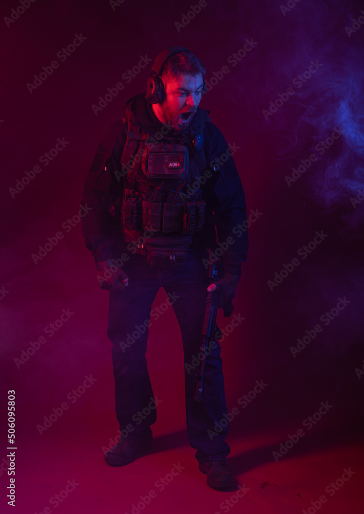 soldier in full gear with weapons. a man in headphones, body armor ...