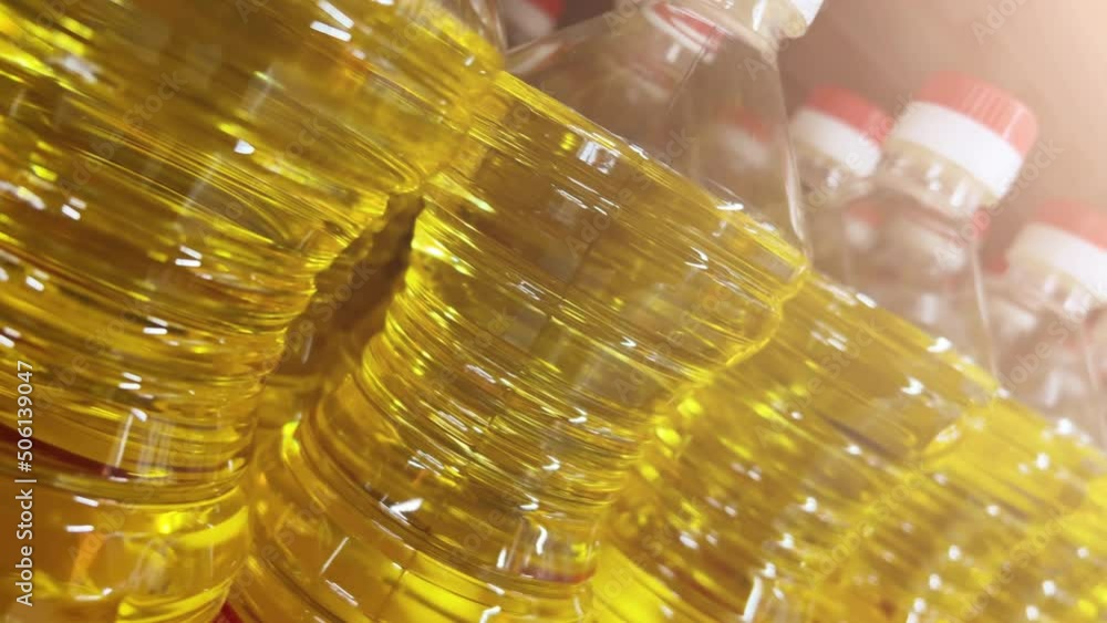 Sunflower or corn oil in plastic bottles line up on the shelf in a ...