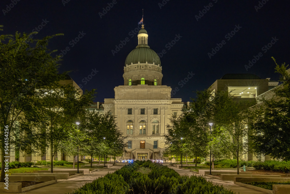 Illuminated Indiana State Capitol: Trees lining the sidewalk and bushes ...