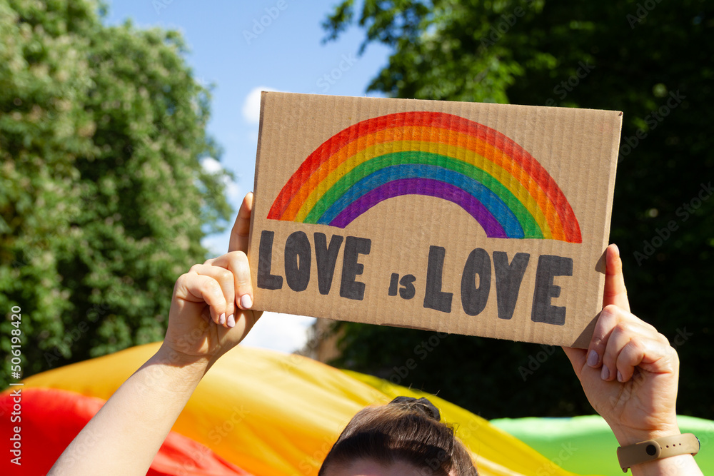 Woman holding placard sign Love is Love with rainbow, symbol of LGBT ...