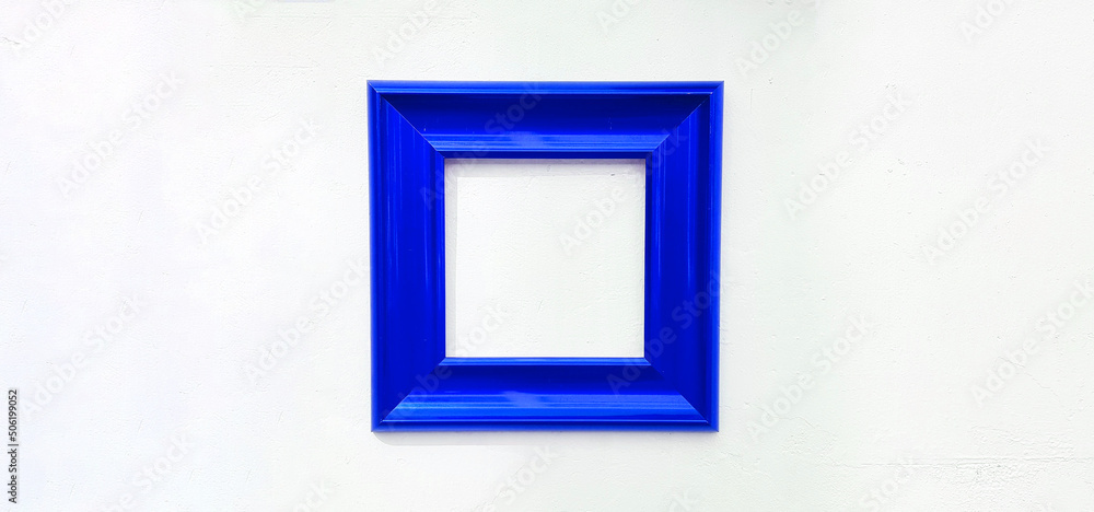 Blue empty picture frame isolated on white wall with copy space. Object ...