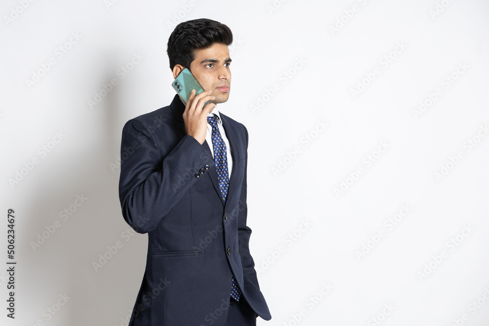 Portrait of a young indian serious business man in a suit talking on ...