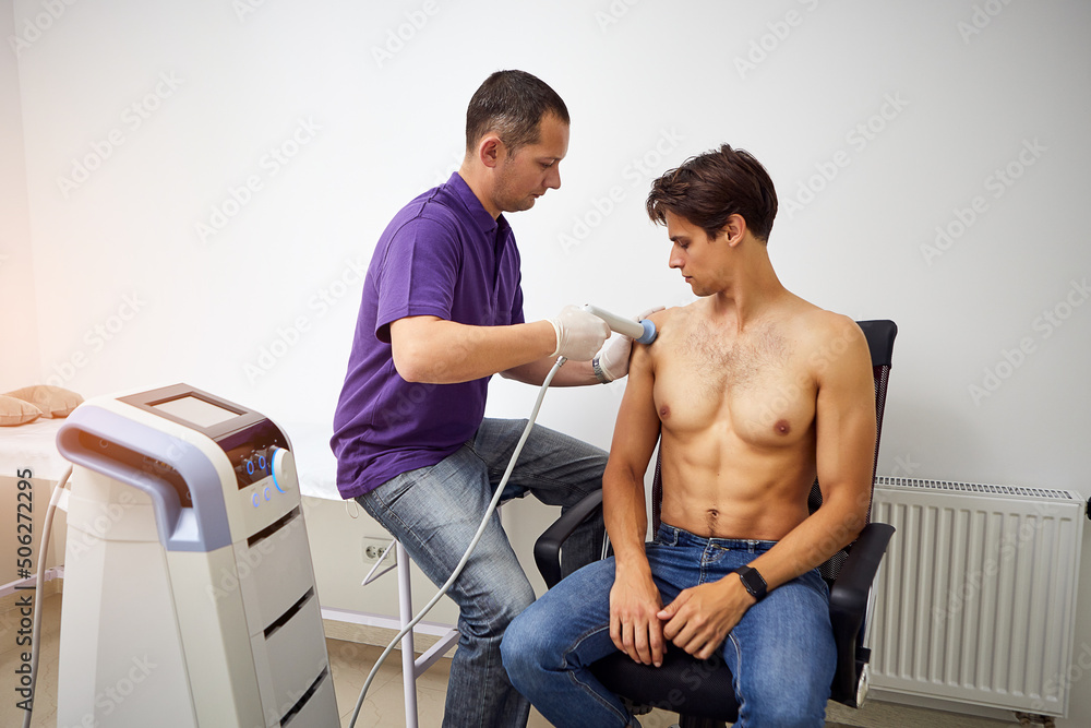 Shock wave therapy of the shoulder joint. Physiotherapist doctor uses ...