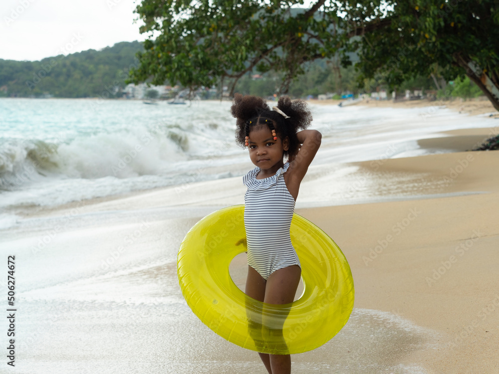 Cute little African girl wearing blue striped swimming suit with yellow ...