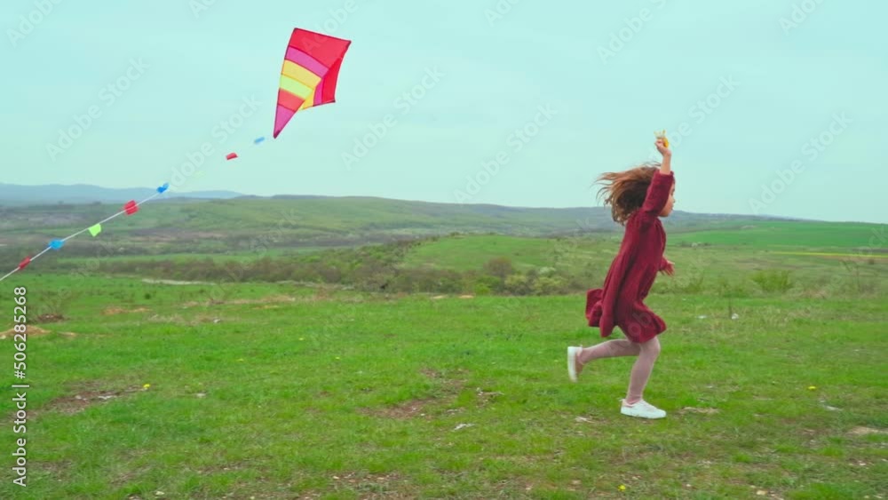 Kid runs with a red kite. Happy little girl playing with flying kite ...