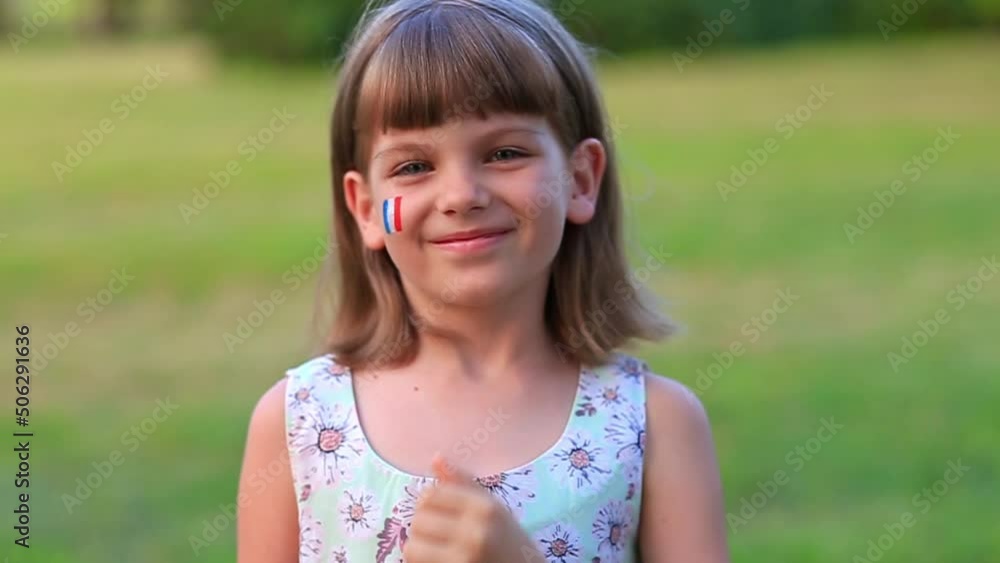 Adorable little girl smile at camera with cheeks painted in flag of ...
