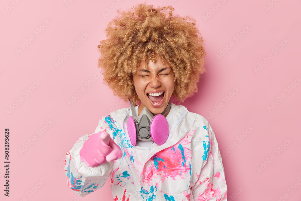 Cheerful young woman wears radiation protective suit gas mask around ...