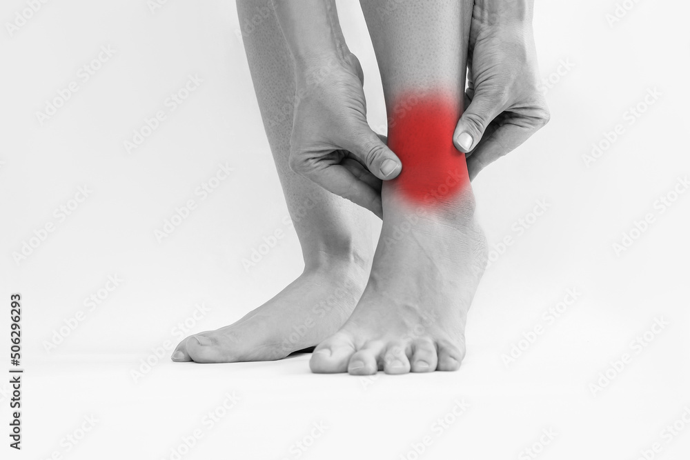 Cropped shot of a young woman touching painful twisted or broken ankle ...