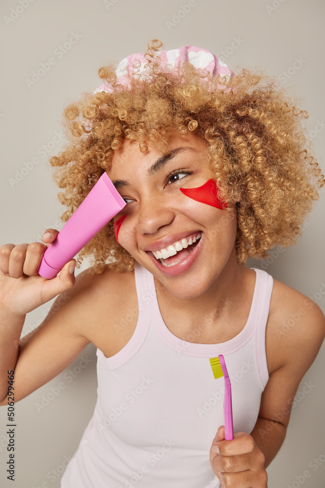 Carefree cheerful woman holds toothbrush and tube of toothpaste ...