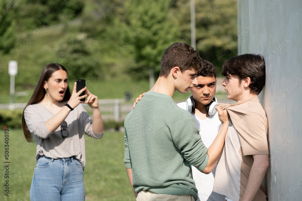 Two bullies menacing teenager boy and girl filming on phone. Cyber ...