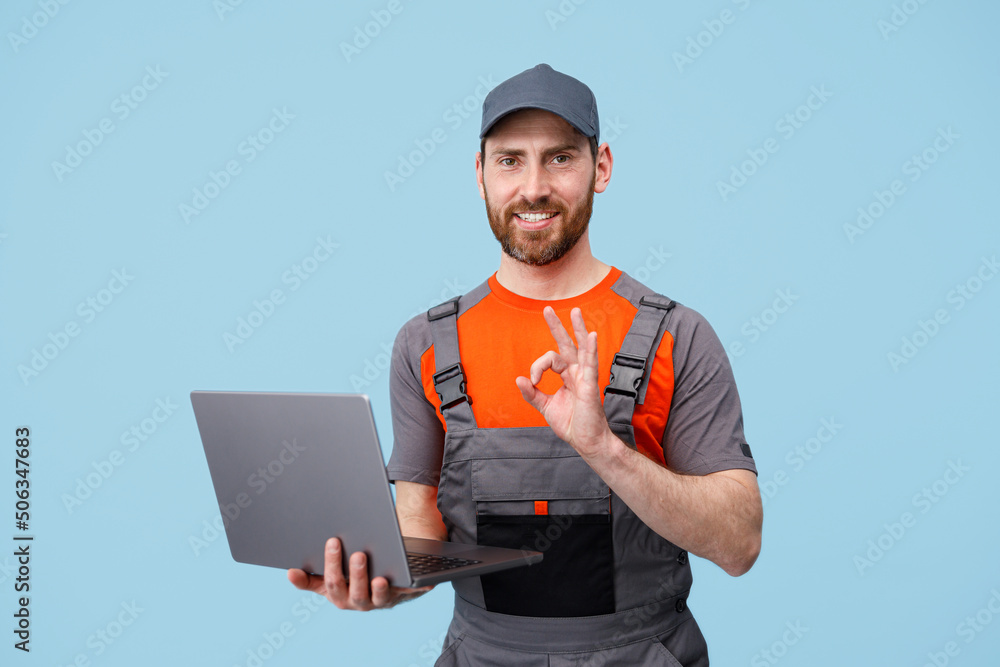 Handsome smiling delivery man in uniform with laptop looking at camera ...