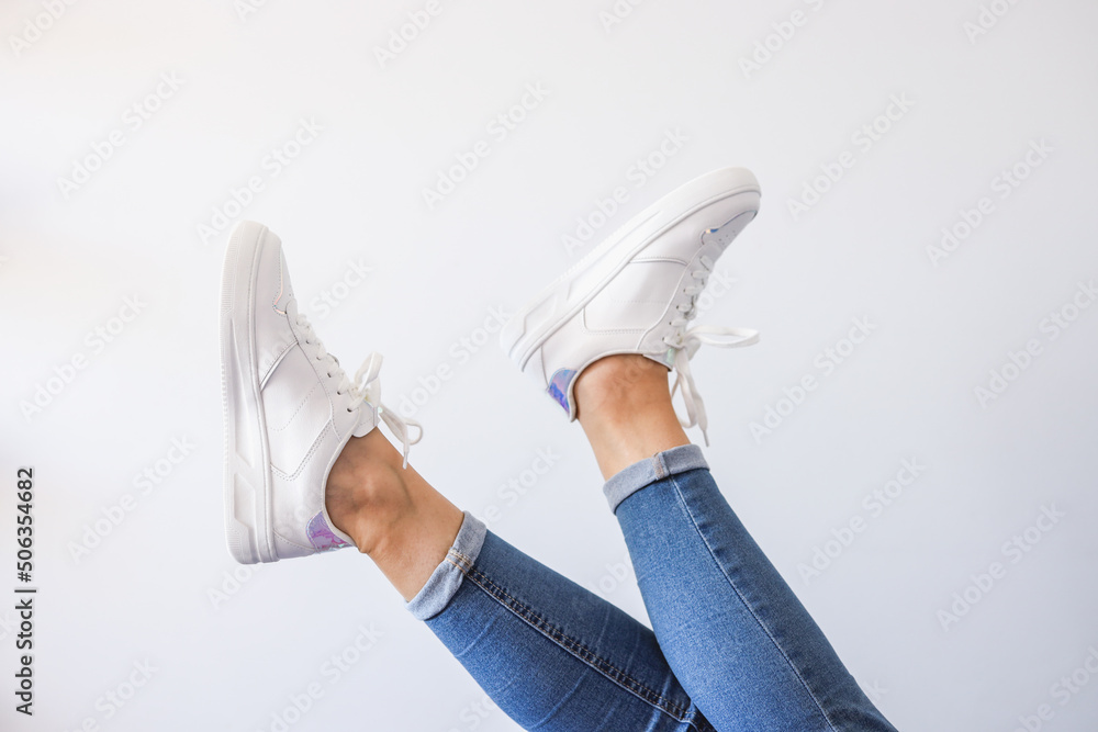 Female feet in sneakers raised up. Isolated on white background. Stock ...