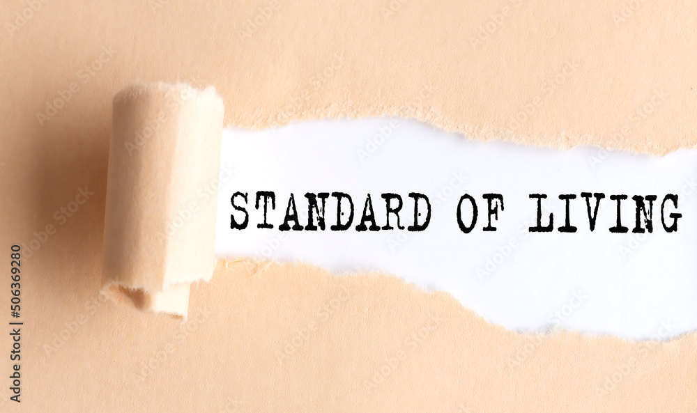 The text STANDARD OF LIVING appears on torn paper on white background ...