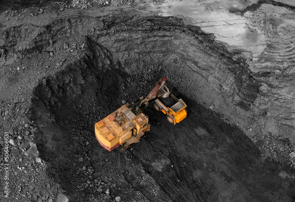 Coal mining in an open pit. Mining excavator loads coal in haul truck ...