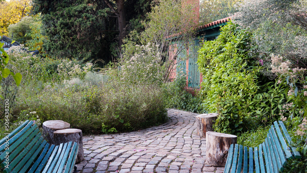 old stone pathway between colorful bushes and tall trees in Carlos ...