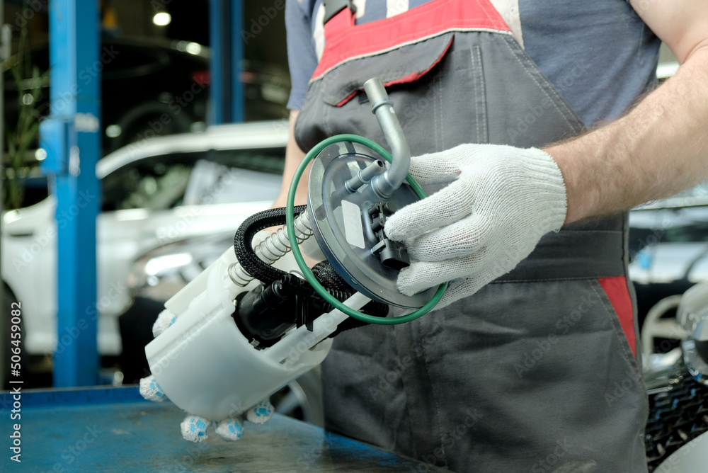 Car maintenance at a car service. An auto mechanic holds a new fuel ...
