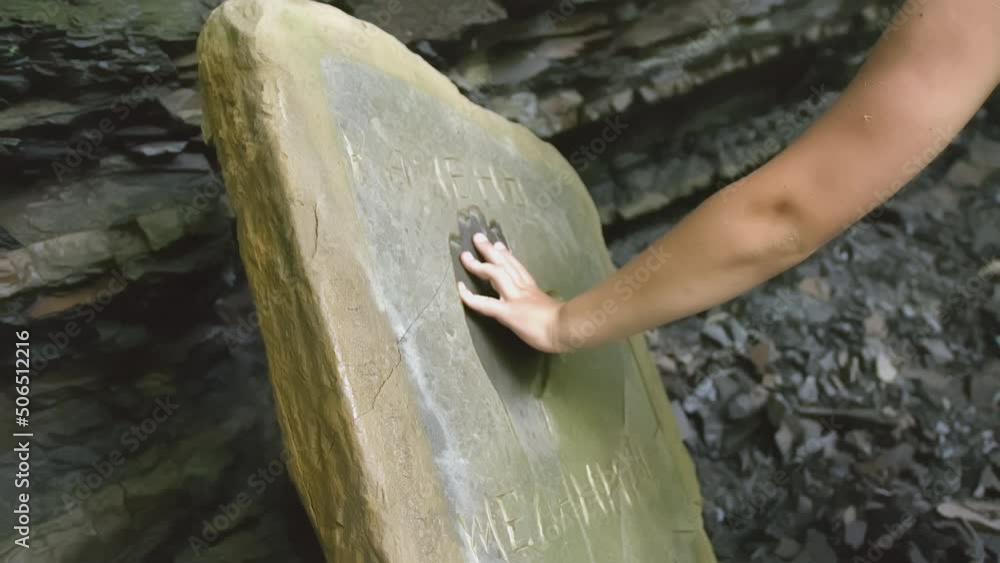 A person leans his hand against a stone with a recess in the shape of a ...