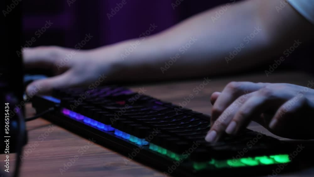 Gamer typing on backlight keyboard close-up, man playing video game ...