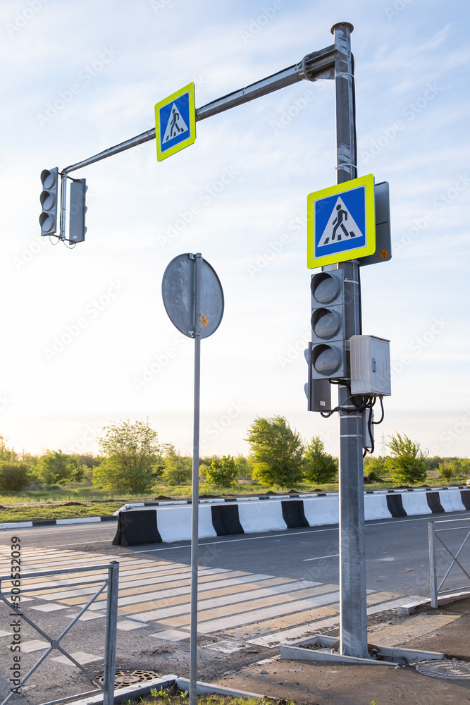 On the road there is a pole with two traffic lights and two traffic ...