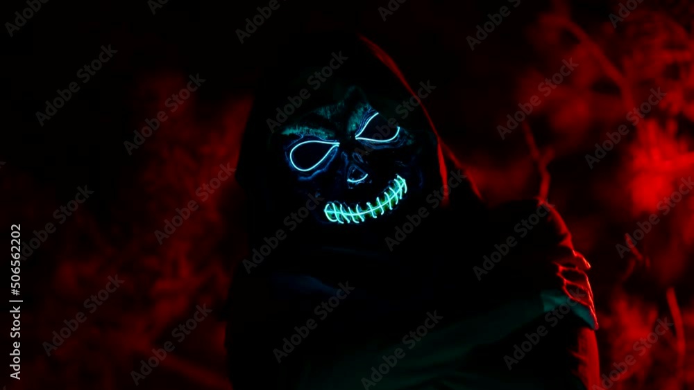 Portrait of a girl with a neon skull mask in the dynamic spotlight. The ...