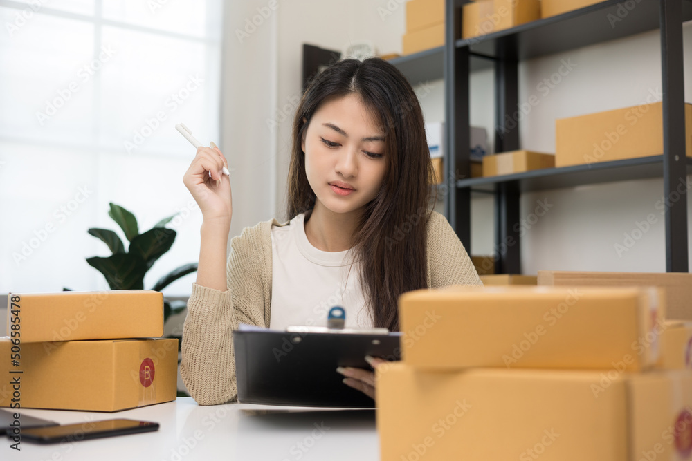 Busy young asian entrepreneur woman checking product on stock take note ...