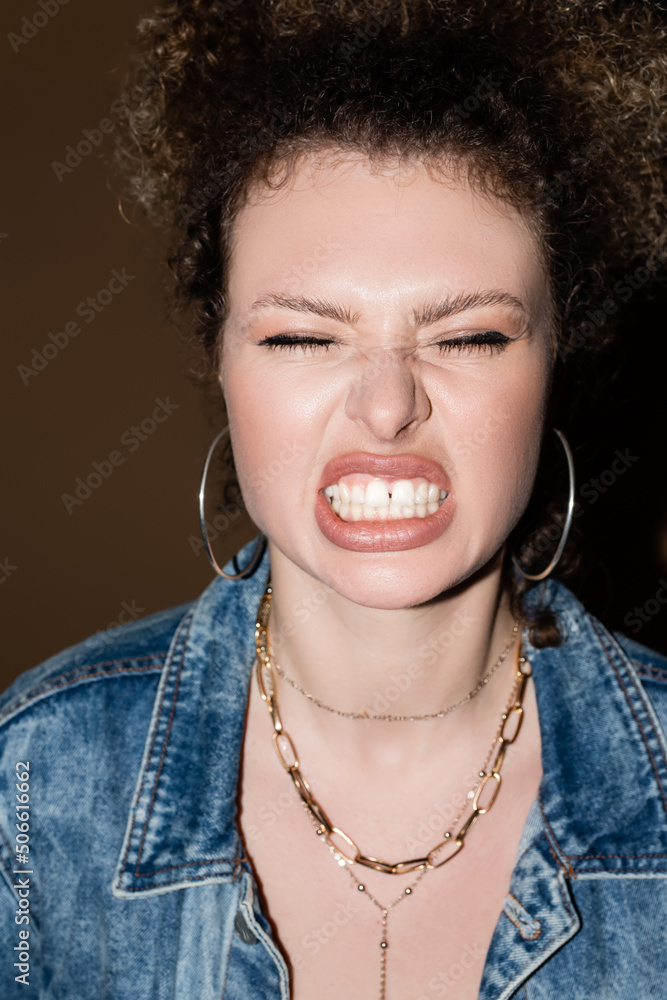 Angry model in denim jacket and accessories showing teeth on black ...