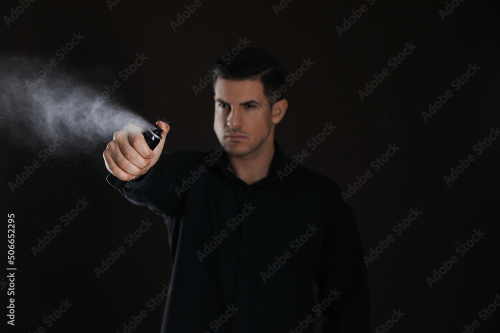 Man using pepper spray against black background, focus on hand Stock ...