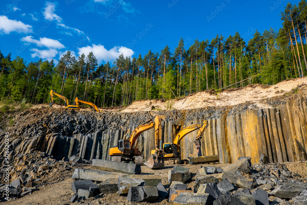 Basalt mining. Yellow excavators in a basalt quarry. Basaltic and ...