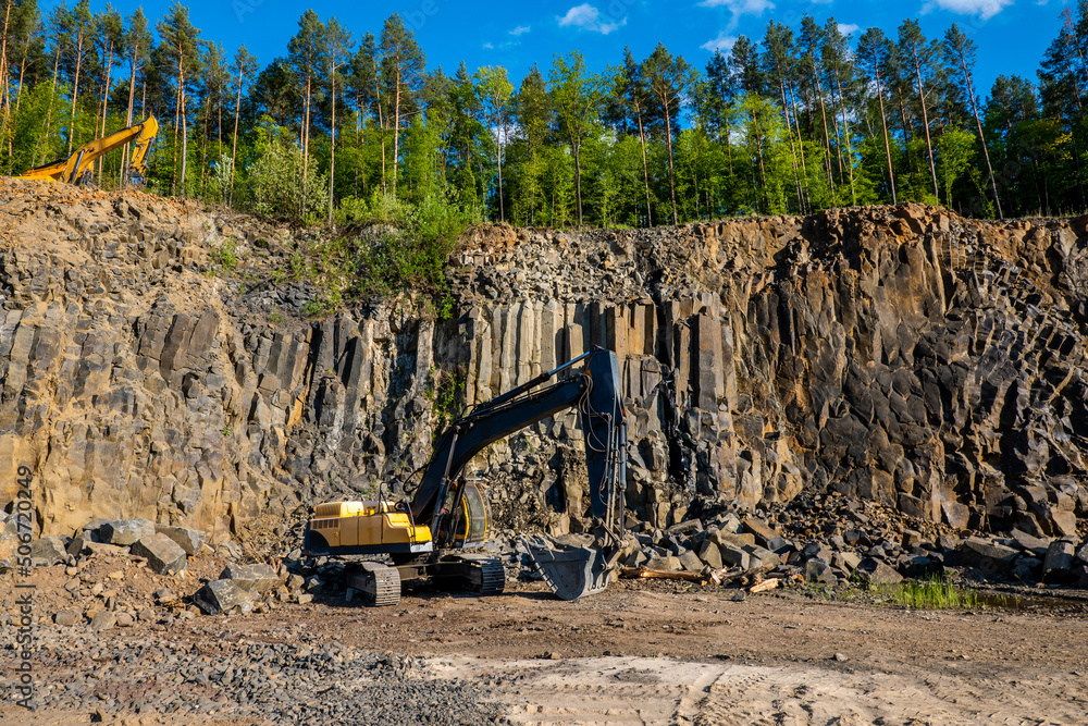 Basalt mining. Yellow excavators in a basalt quarry. Basaltic and ...