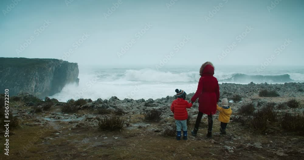 Young mother with children came to the ocean edge to watch big storm ...