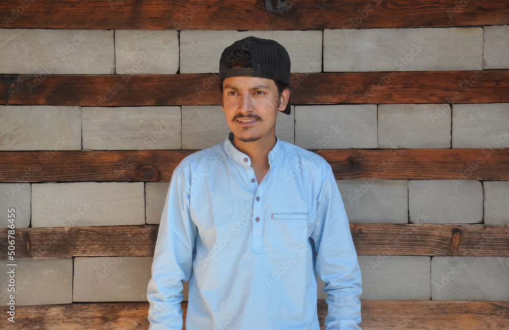 A good looking Indian young guy wearing cap backwards, looking sideways ...