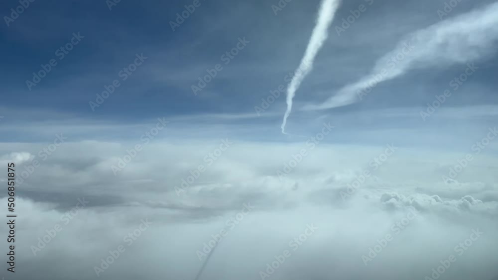 Sky view from a jet cockpit during flight overflying clouds and bellow ...