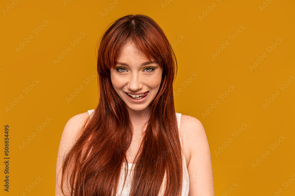 Positive ginger girl with beautiful toothy smile licking her white ...