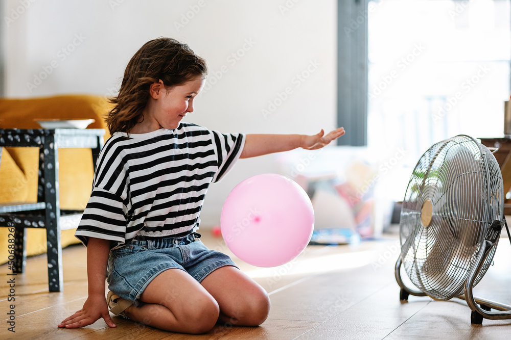 Little girl at home sitting on the floor playing with fan Stock Photo ...