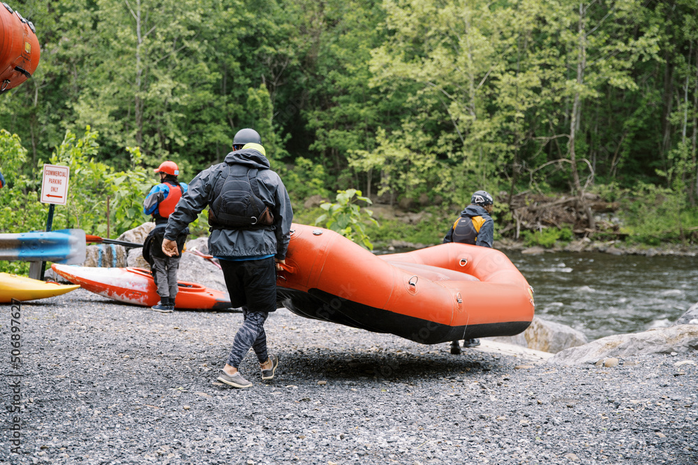 Two men carrying an inflatable sport whitewater raft to a rapid river ...