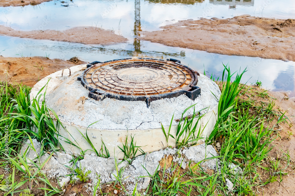 Installation of a heavy cast iron sewer manhole on a well before paving ...