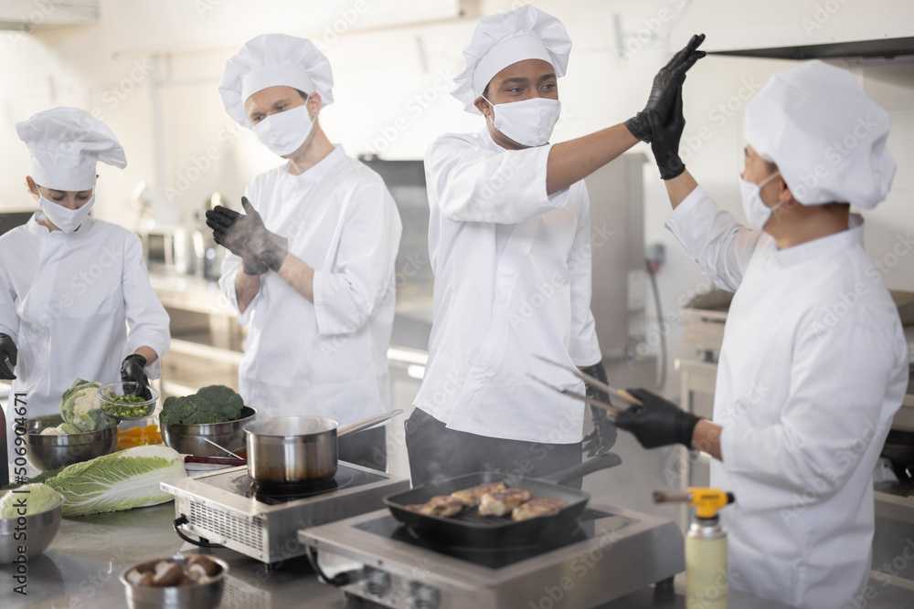 Multiracial team of cooks giving five with hands each other, while ...