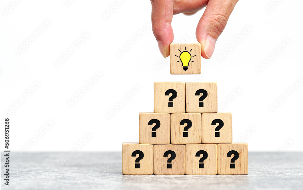 Hand arranged wooden blocks in pyramid shape with icon question mark ...