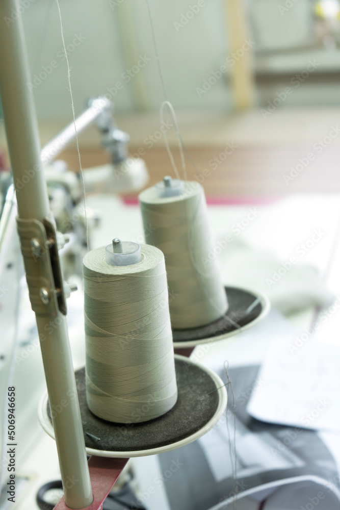Close-up of a two spools of thread on the industrial sewing machine. A ...