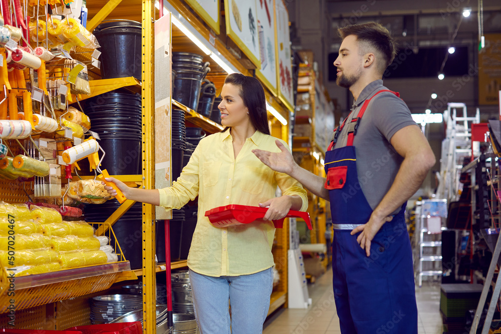 Shopping in hardware shop. Male salesman at counter advises female ...