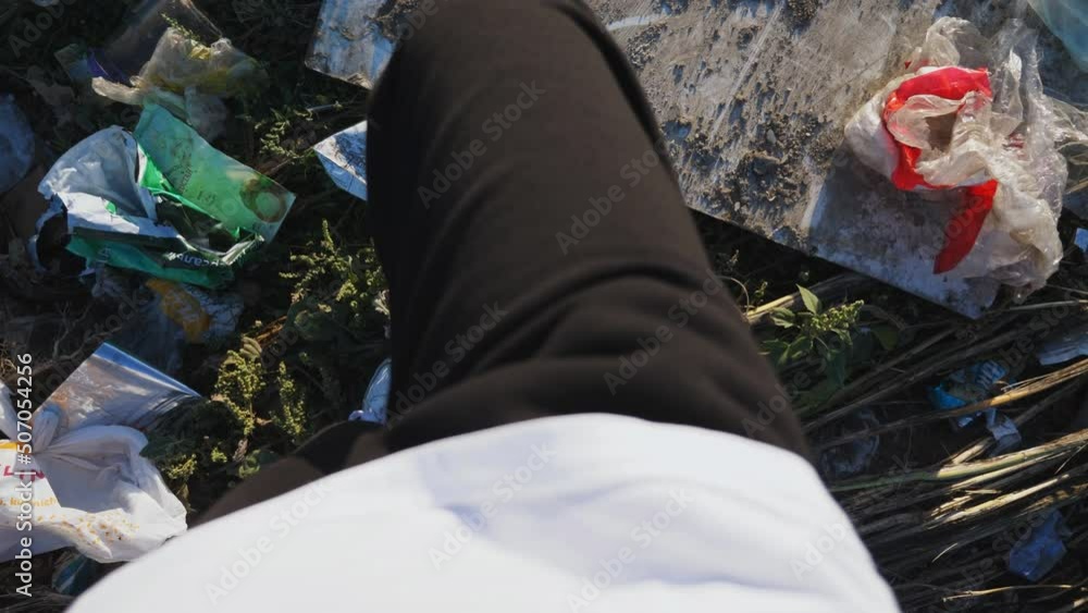 POV feet of little girl in sneakers stepping on garbage at junkyard ...